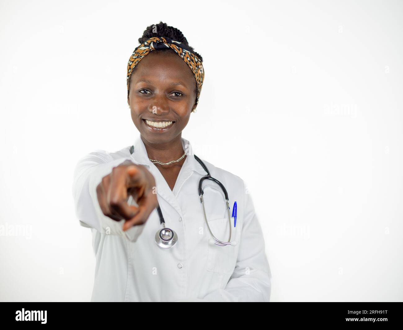 Young female doctor pointing at camera while smiling. Looking at camera ...