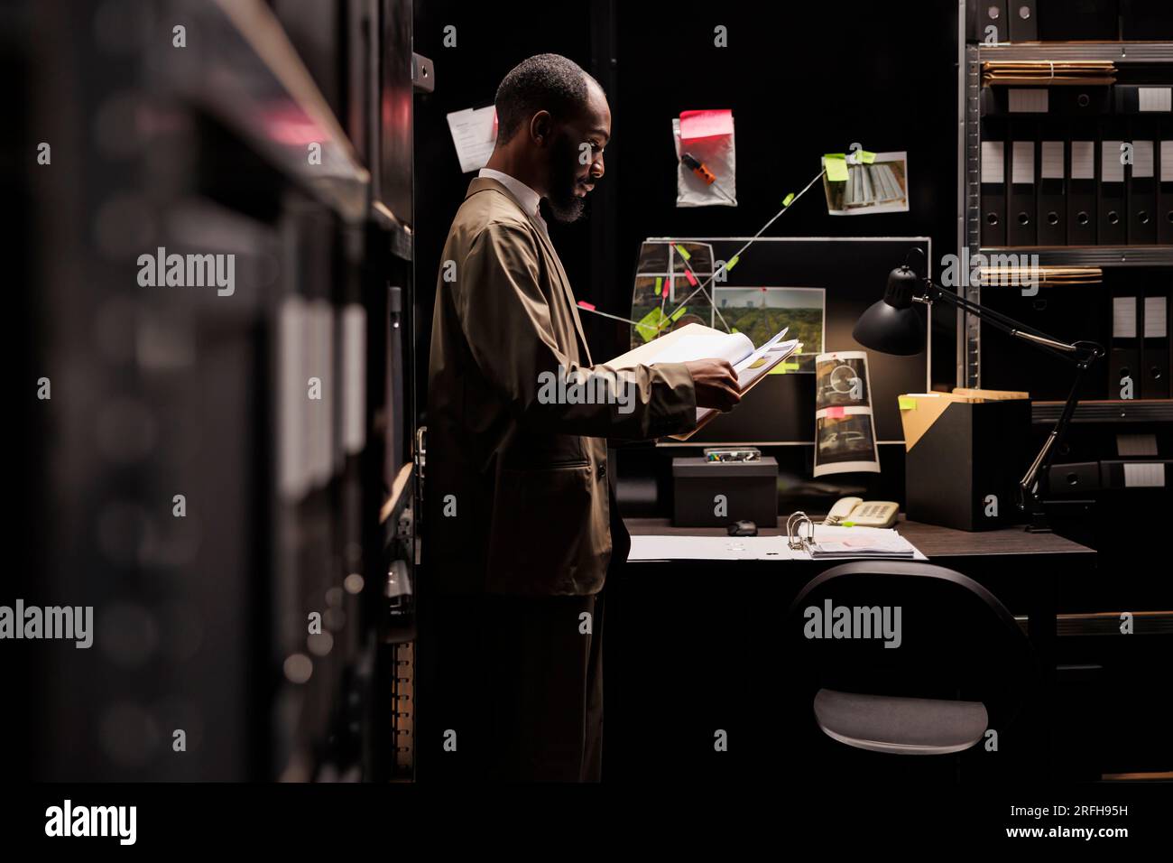 African american cop standing near detective board, reading report to ...