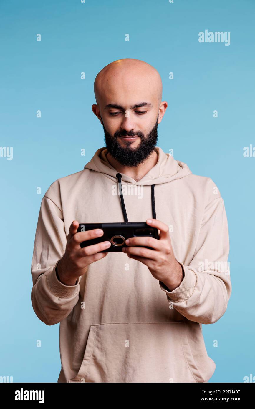 Arab man using smartphone application and playing video game during ...