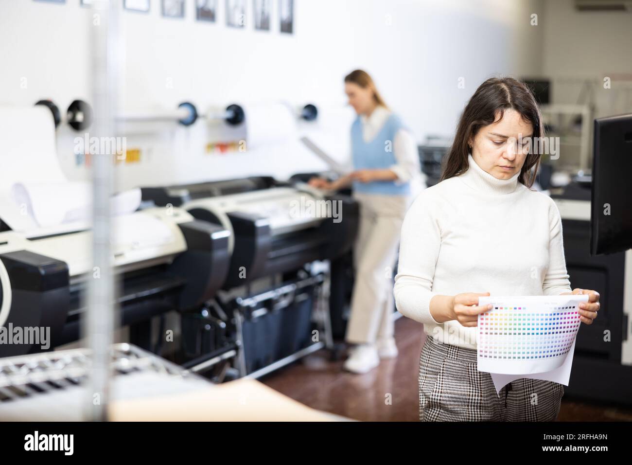 Printing office manager looking at colour test page for printer Stock ...