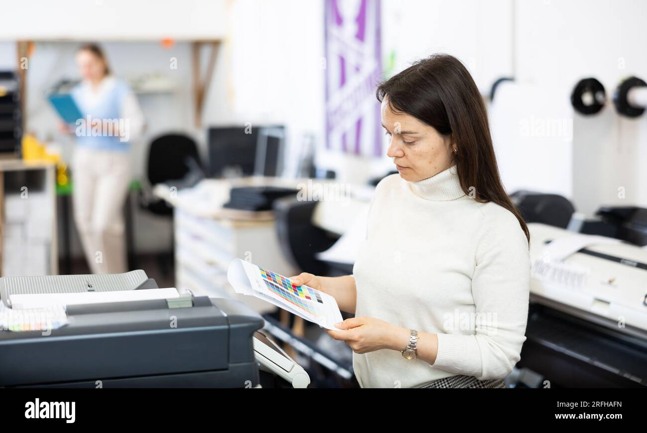 Printing office manager looking at colour test page for printer Stock ...
