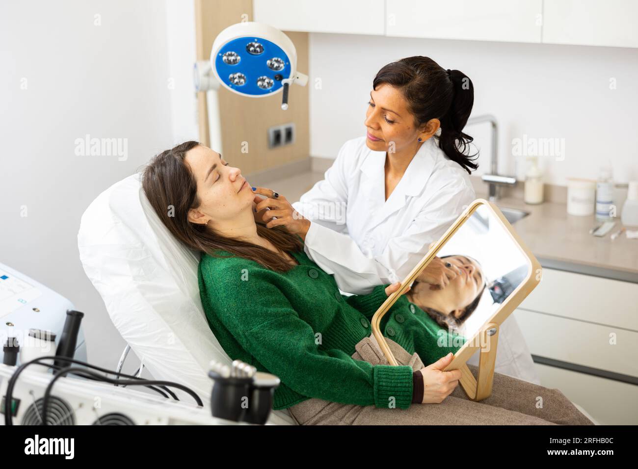 Female beauty doctor looking at woman's face during examination Stock ...