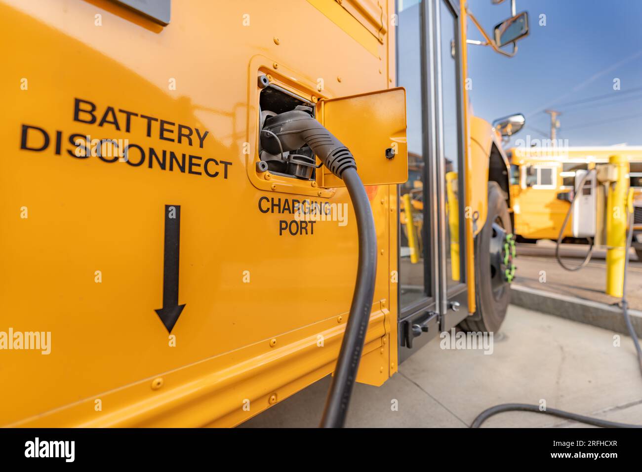 Yellow electric school bus plugged in at a charging station Stock Photo ...