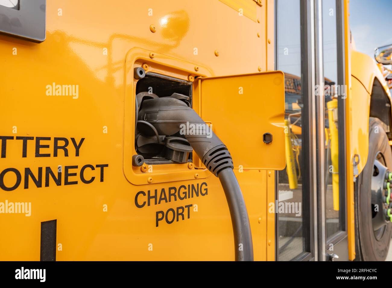 Yellow electric school bus plugged in at a charging station Stock Photo ...