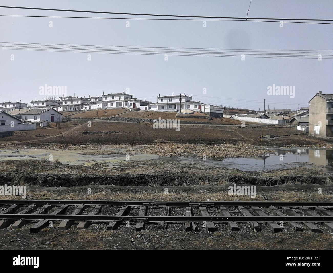 A rural landscape with a train track and a village in the background ...
