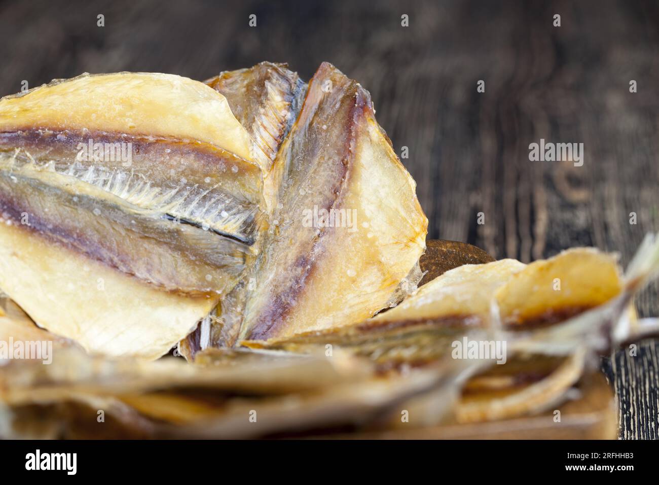 dried and butchered small fish on a wooden table, small fish gutted and ...