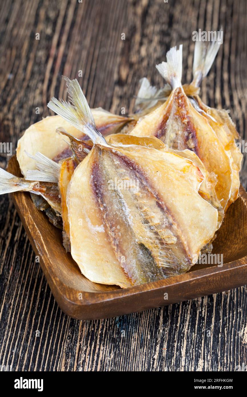 dried and butchered small fish on a wooden table, small fish gutted and ...