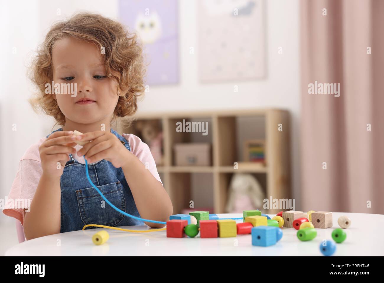 Motor skills development. Little girl playing with wooden pieces and ...