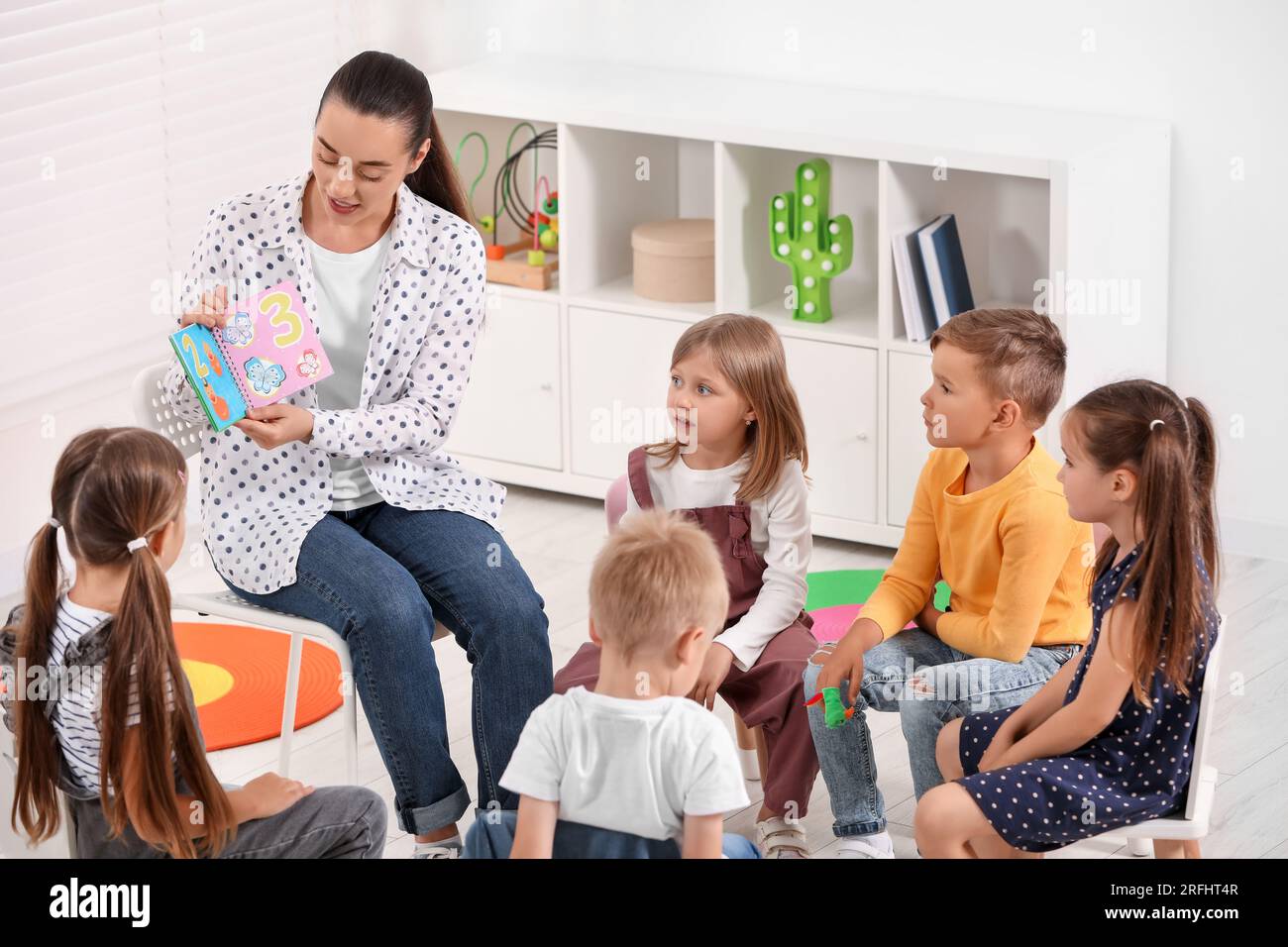 Nursery teacher and group of cute little children learning numbers in ...