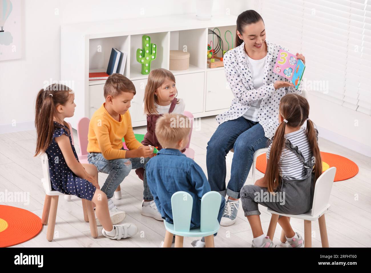 Nursery teacher and group of cute little children learning numbers in ...