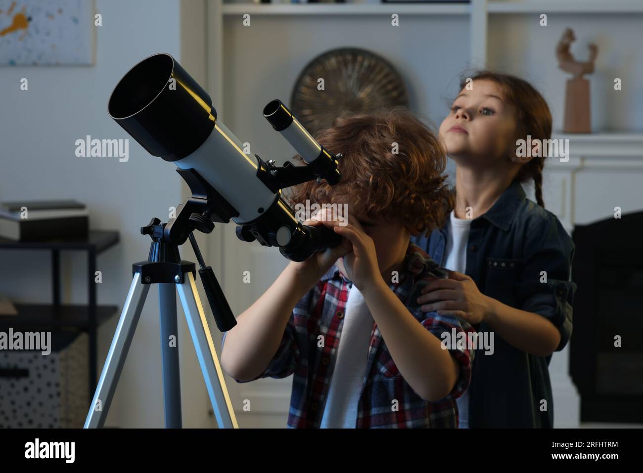 Cute little children using telescope to look at stars in room Stock ...