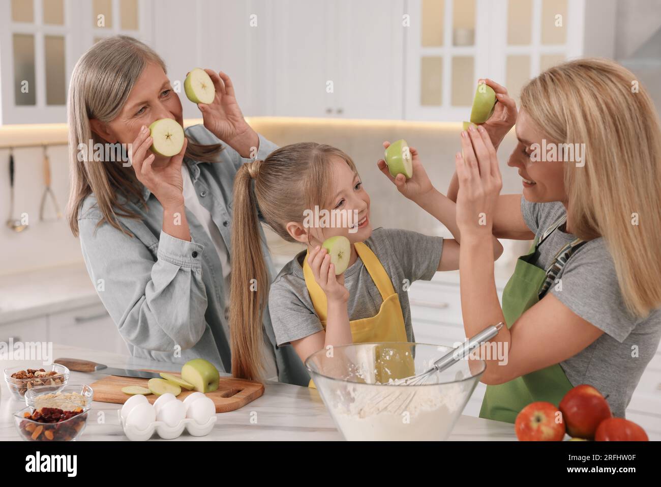 Three generations. Happy grandmother, her daughter and granddaughter having fun while cooking ...