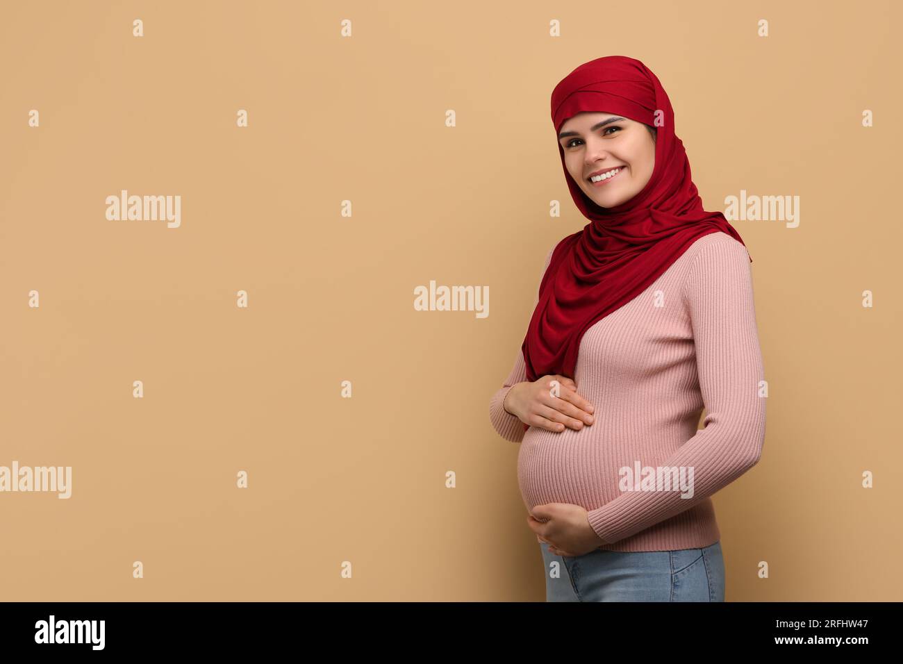 Portrait of pregnant Muslim woman in hijab on beige background, space ...