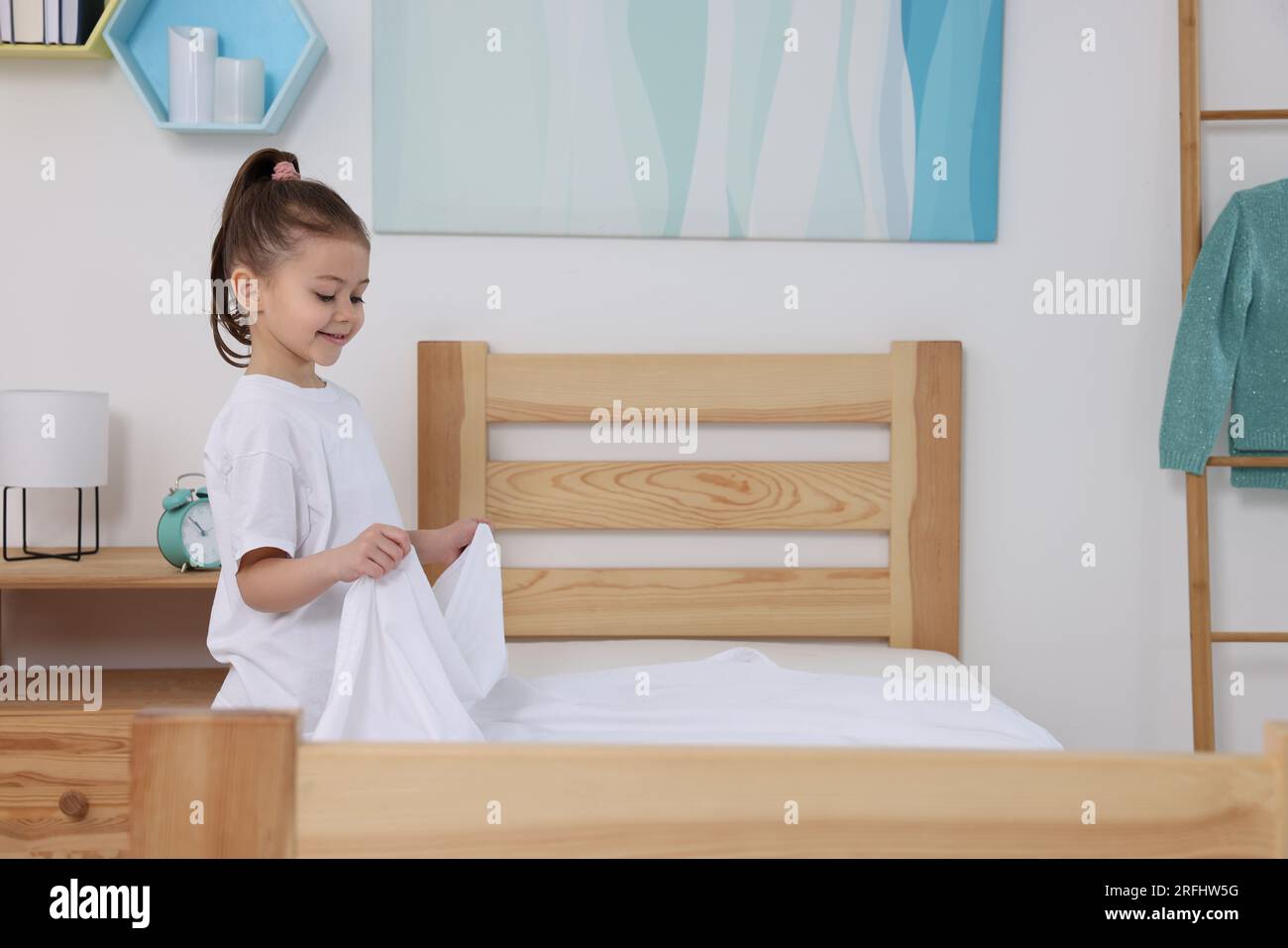 Cute girl changing bed linens in children room Stock Photo - Alamy