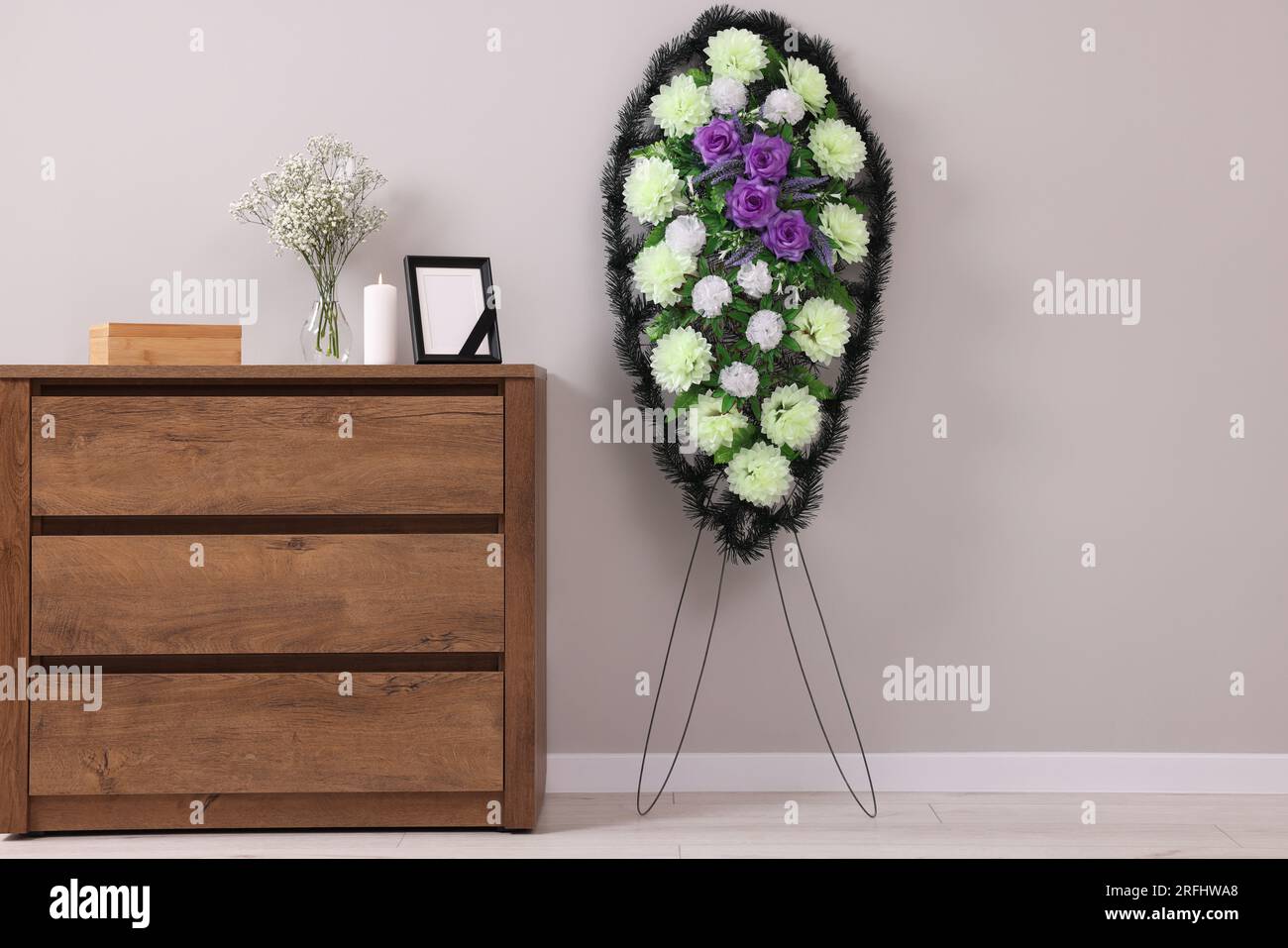 Wreath of plastic flowers and frame with black ribbon, burning candle ...