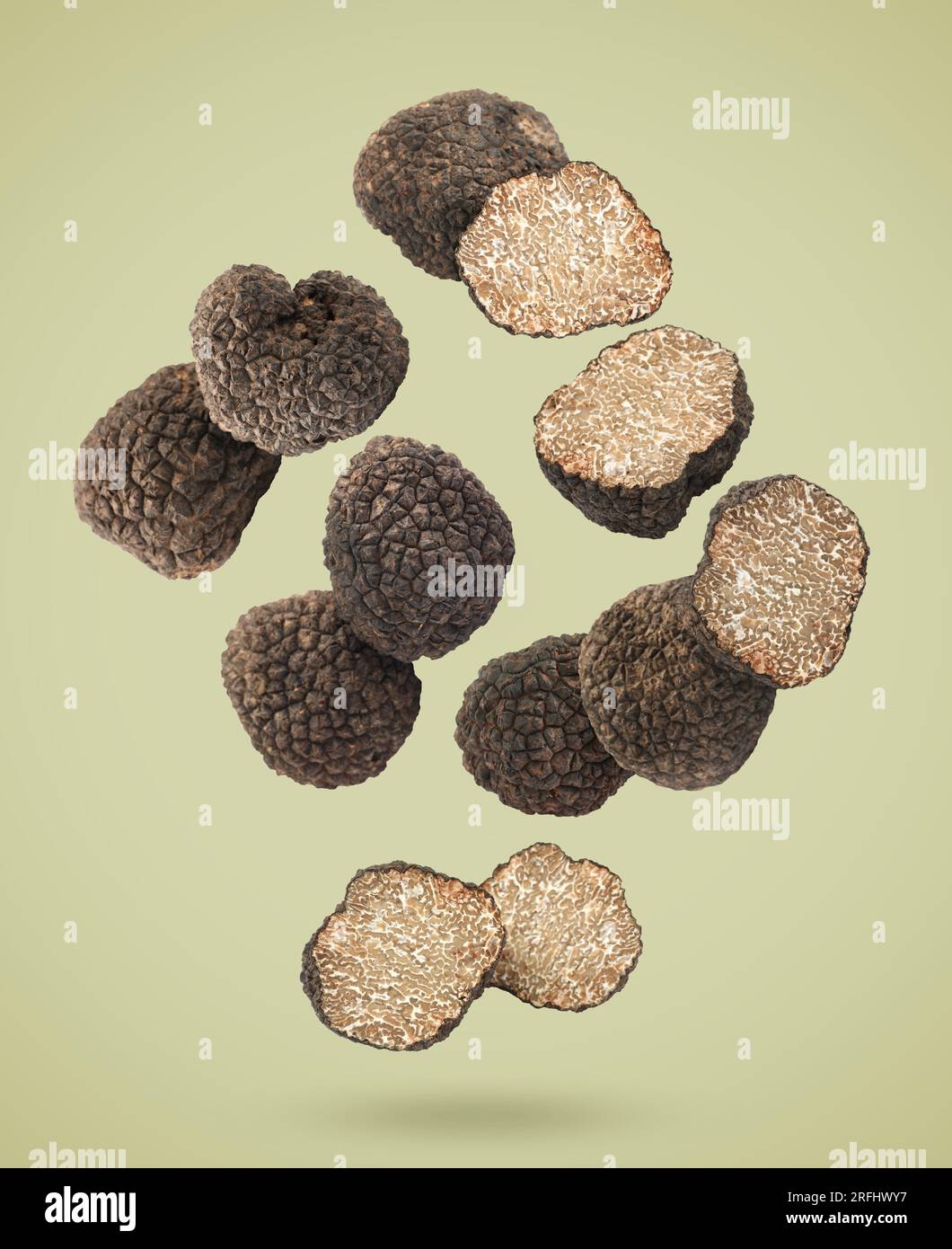 Cut and whole truffles falling on olive color background Stock Photo ...