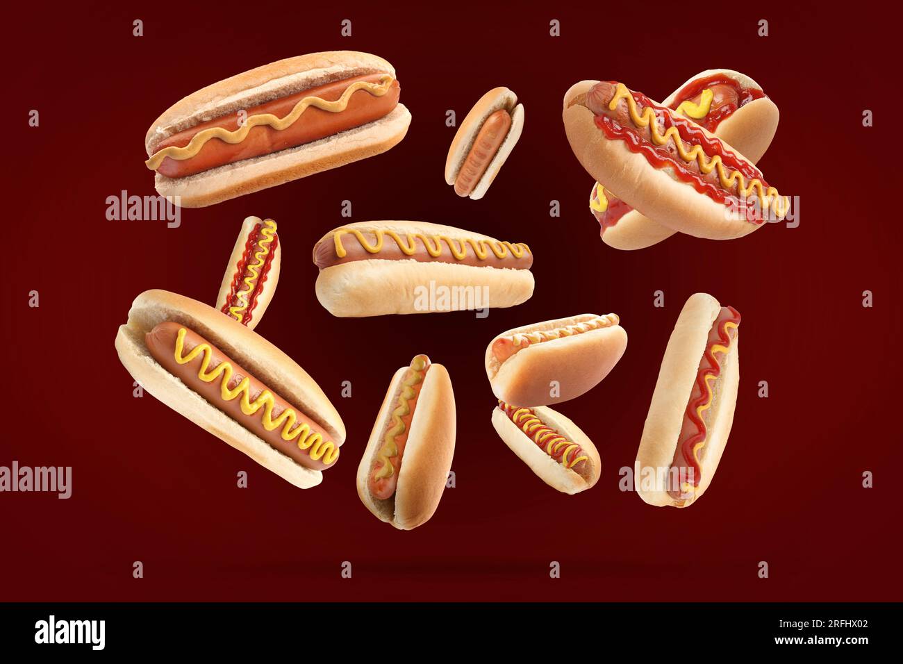 Many tasty hot dogs falling on dark red background Stock Photo - Alamy