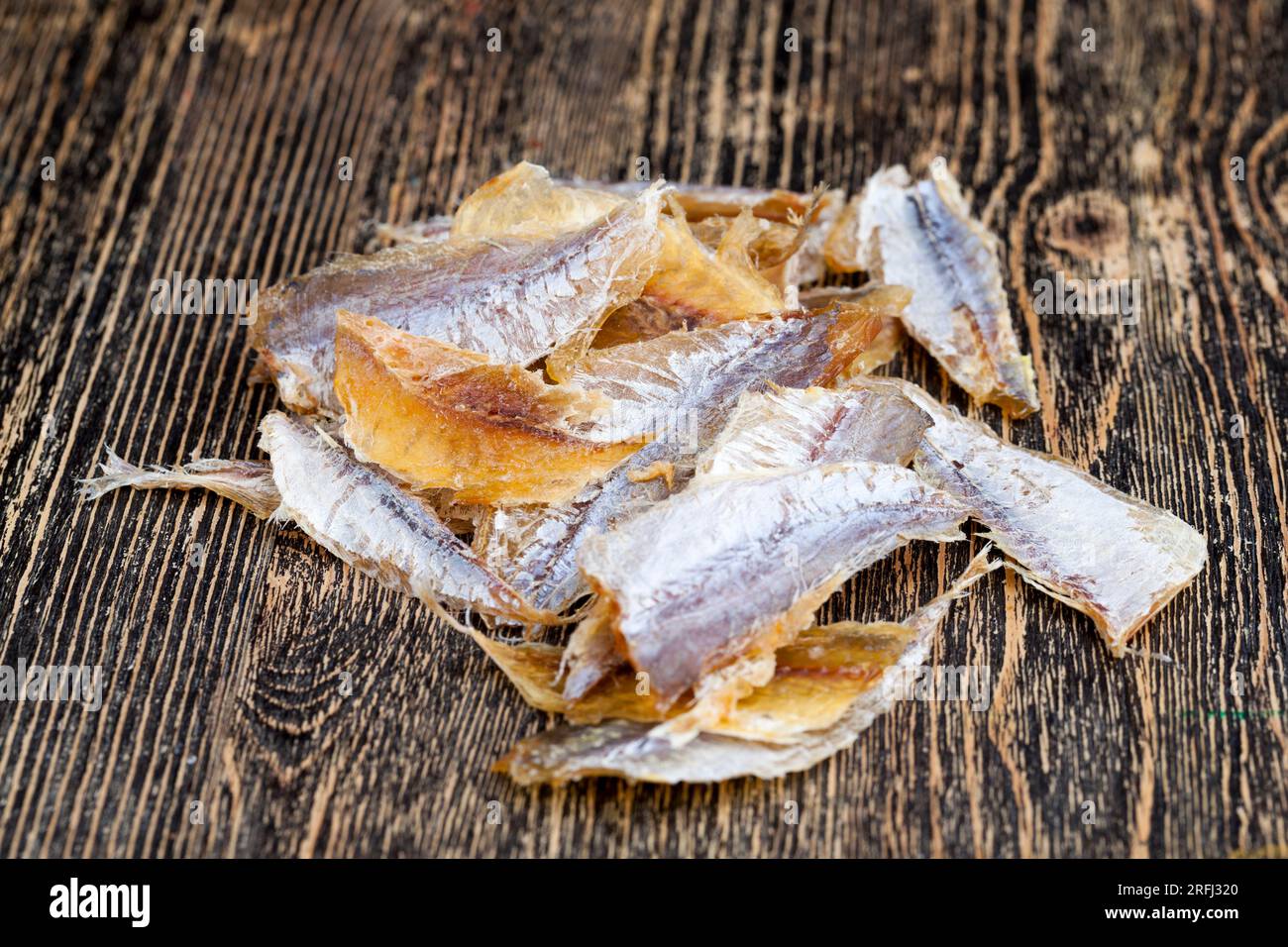 dried and butchered small fish on a wooden table, small fish gutted and ...