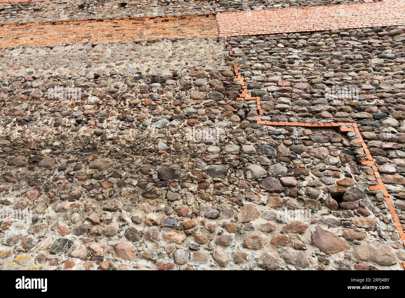 part of the wall of a medieval castle made of stones, cobblestones and ...
