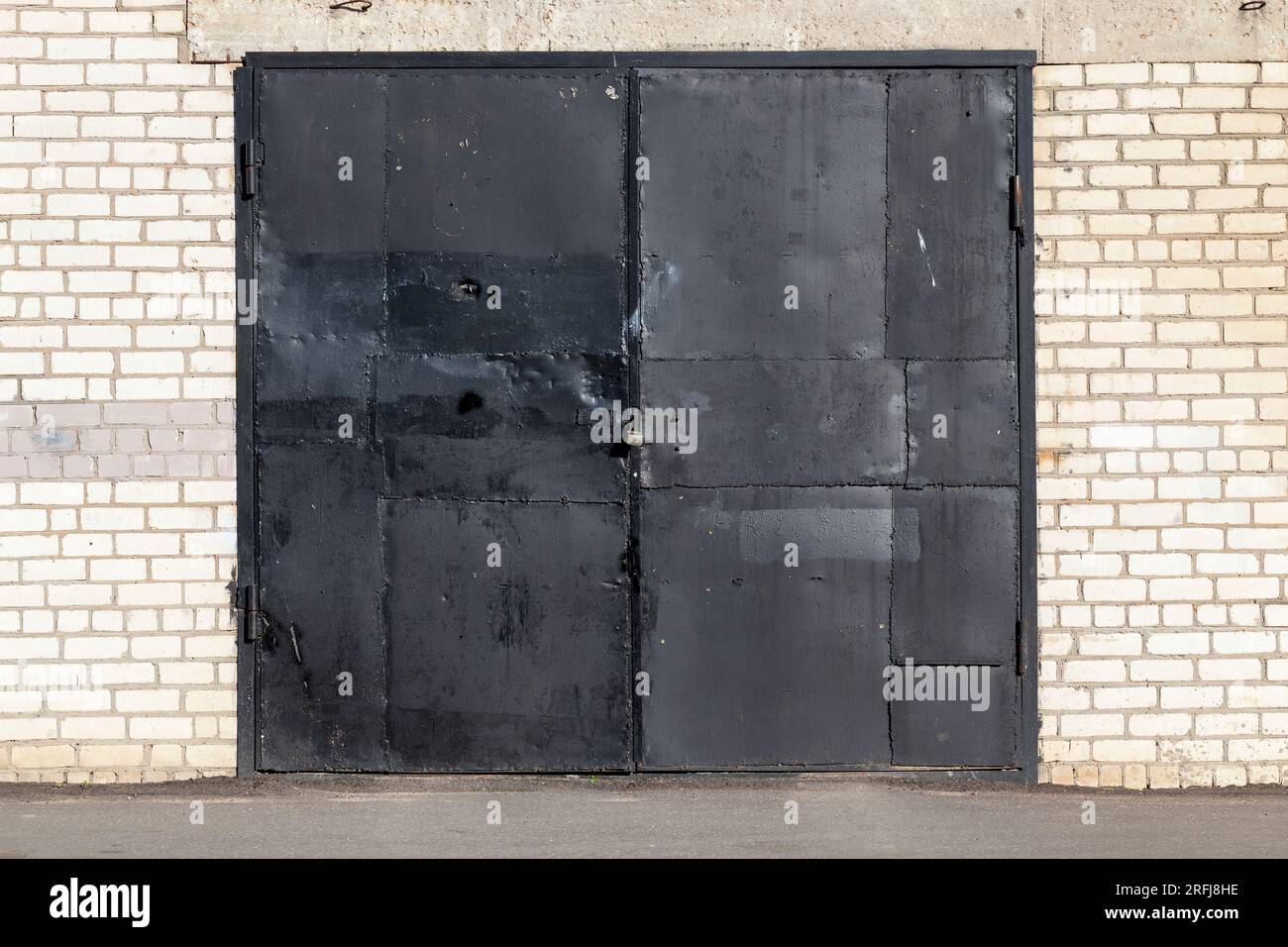 black heavy garage door, painted in black paint and locked old gates ...