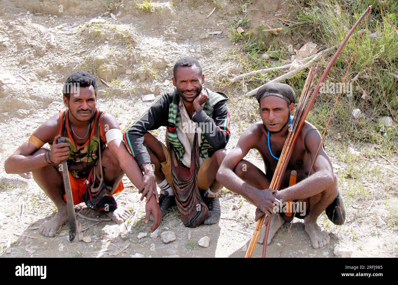 Three men from Papua, Indonesia, sitting on the ground are ready to go ...