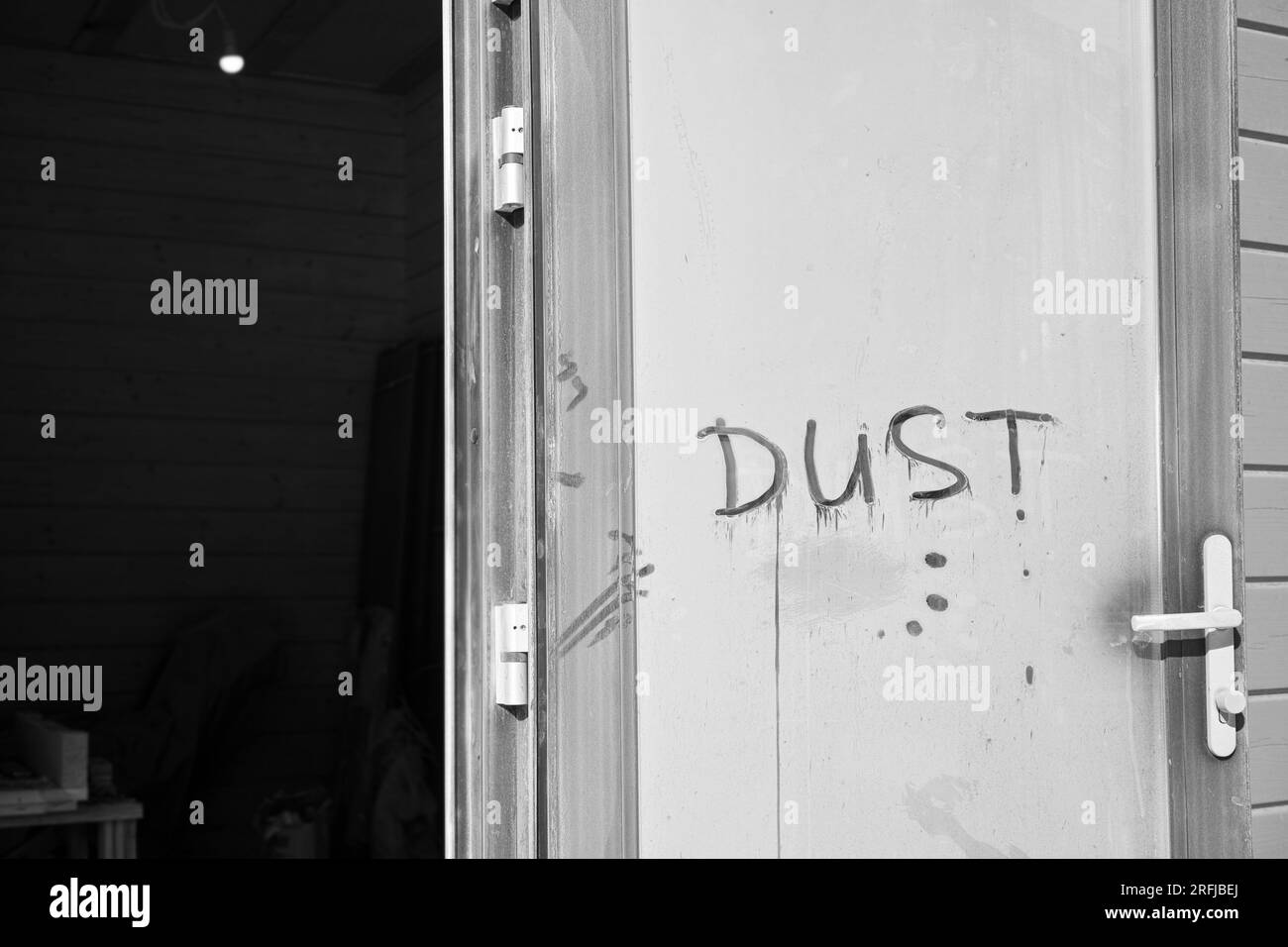 a word Dust written on the dirty and dusty glass entrance door, in ...