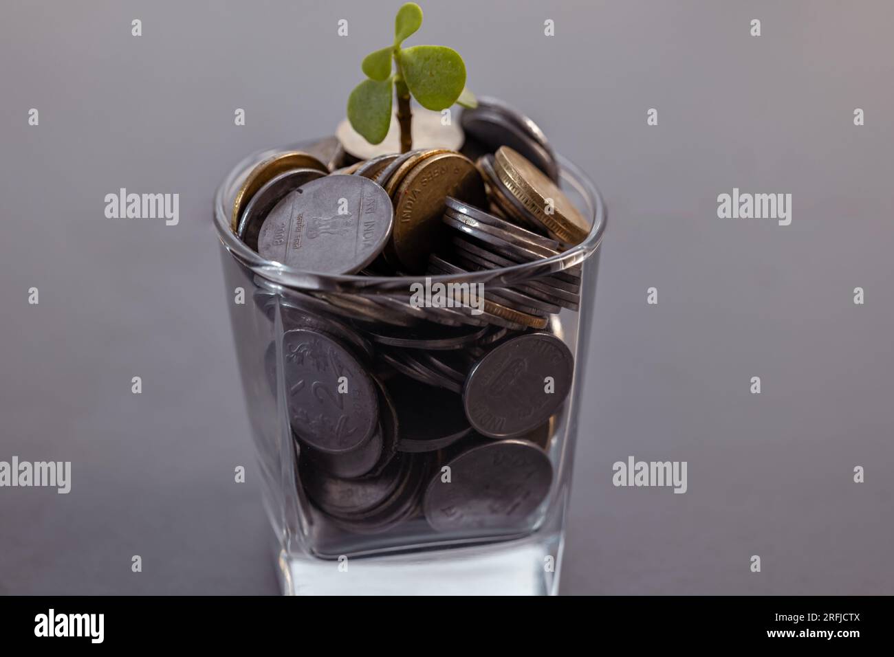This stock image shows a glass filled with Indian coins Stock Photo - Alamy