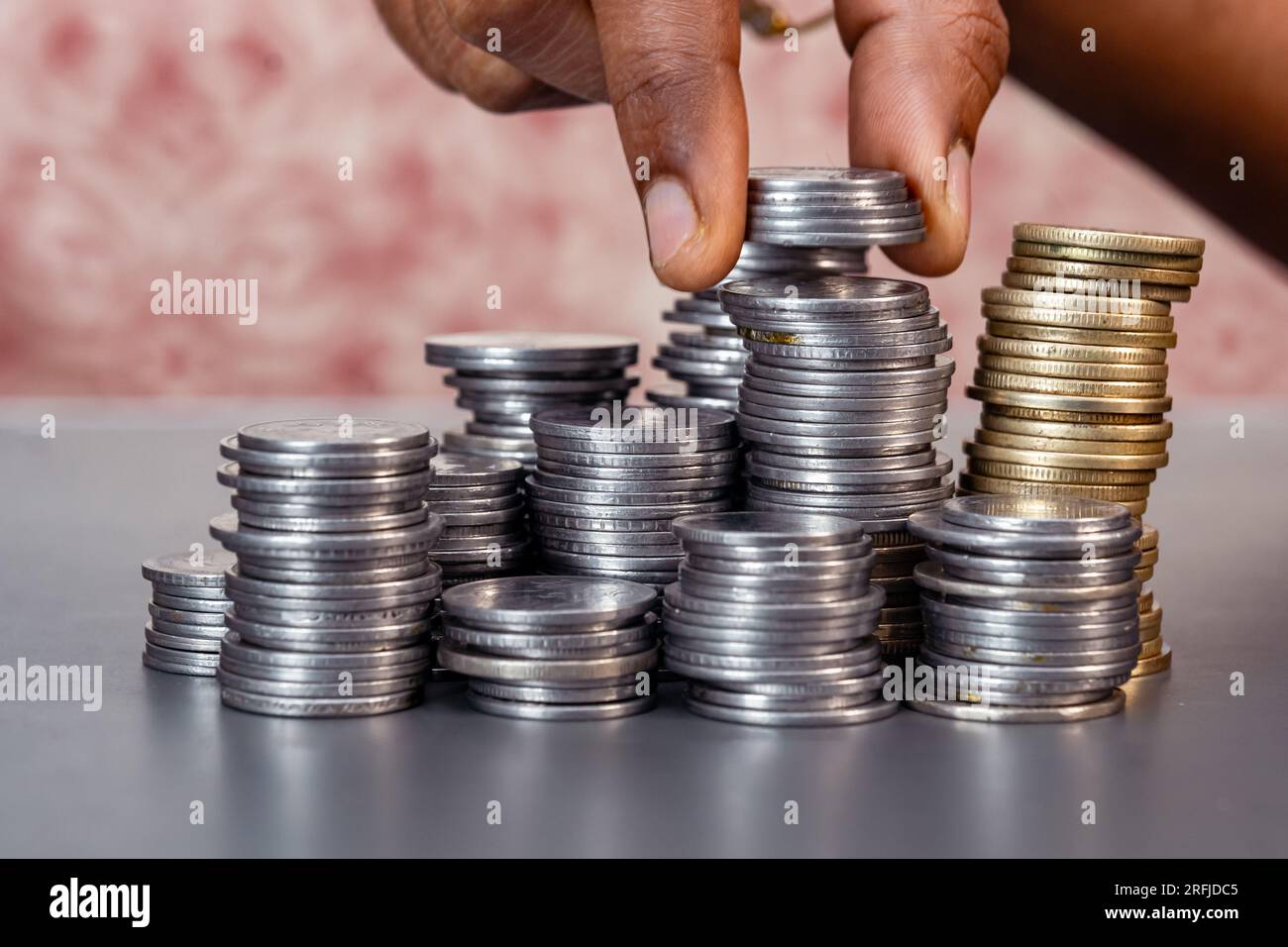 A close-up of a hand arranging a stack of coins in a variety of ...