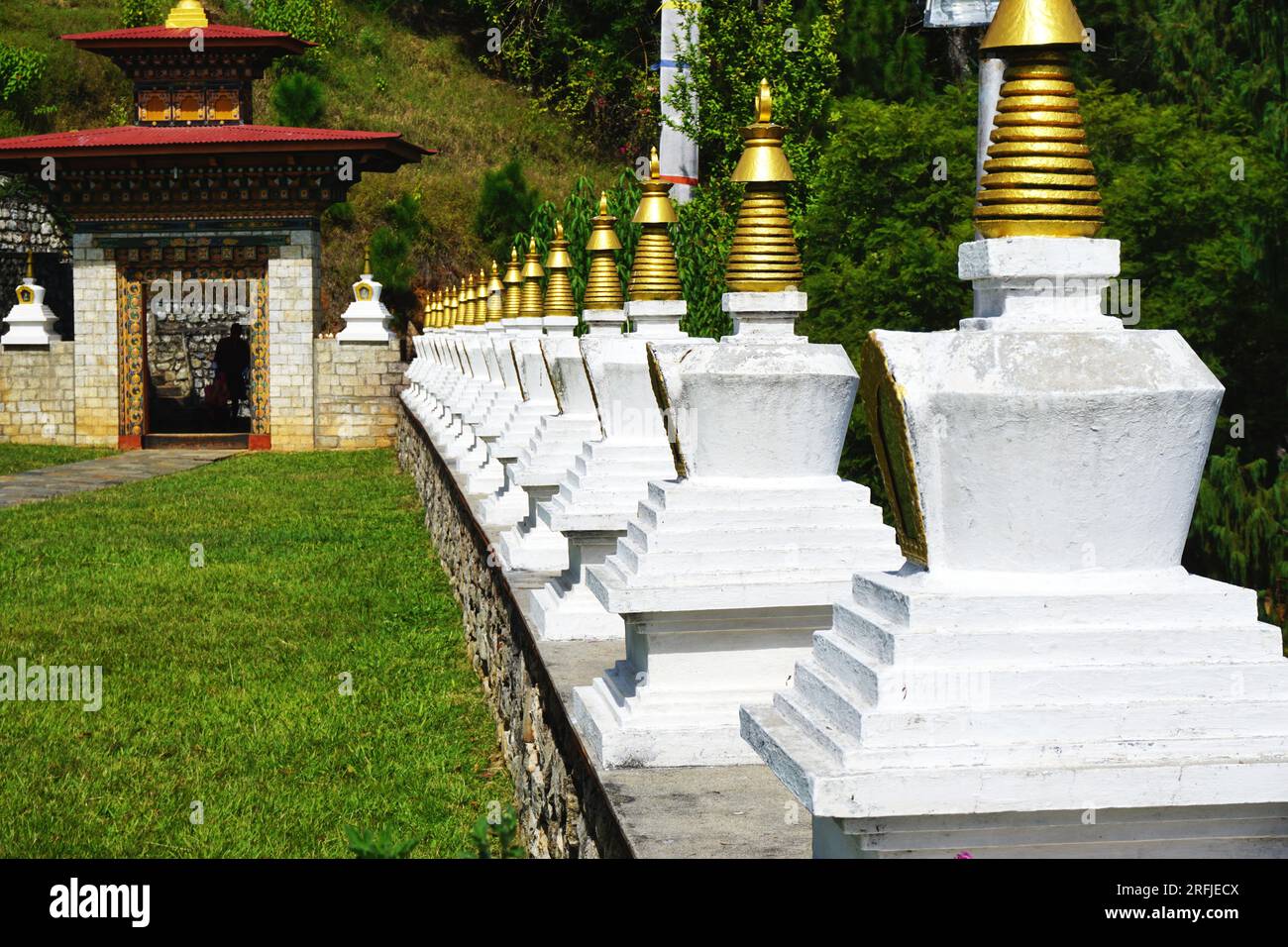 A row of identical whitewashed memorial stupas topped by golden spires ...