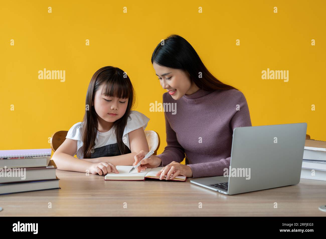 A caring and kind Asian female private tutor is teaching math to a cute ...