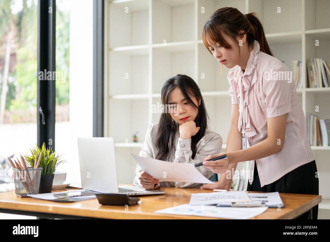 Two concentrated Asian businesswomen or female accountants are ...
