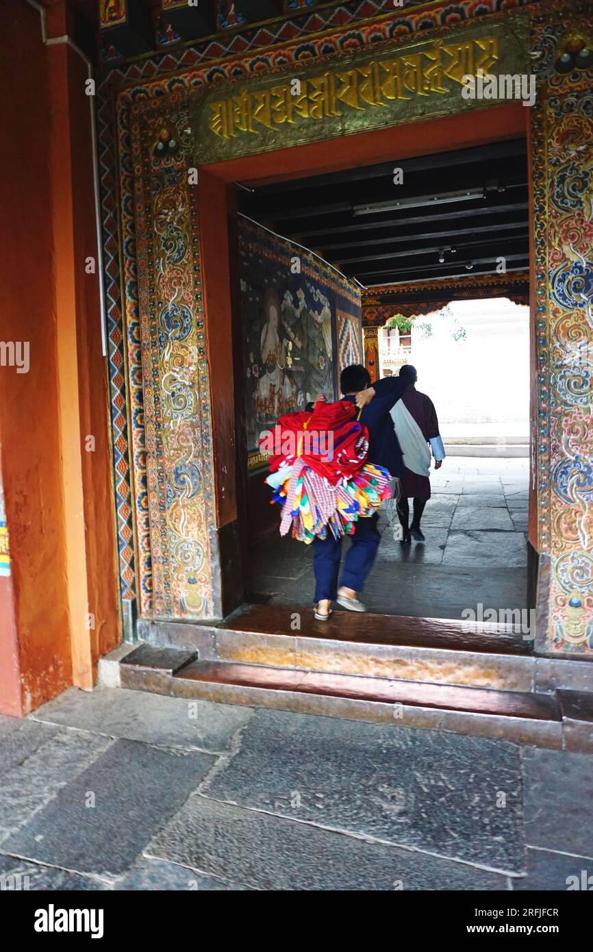 A worker carries a load of colorful cloth temple banners and ...