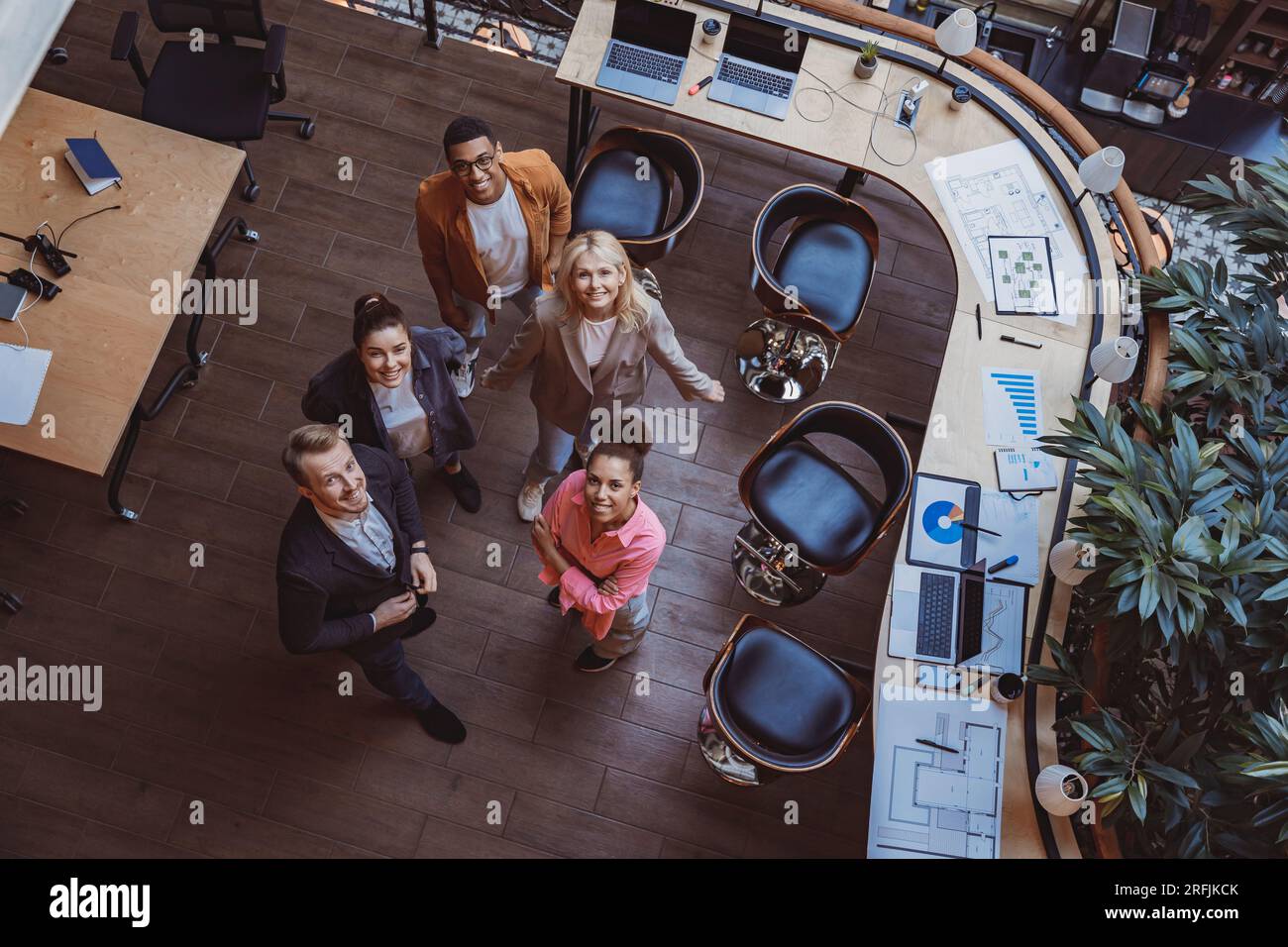 Group of coworkers standing at office and looking up at camera ...