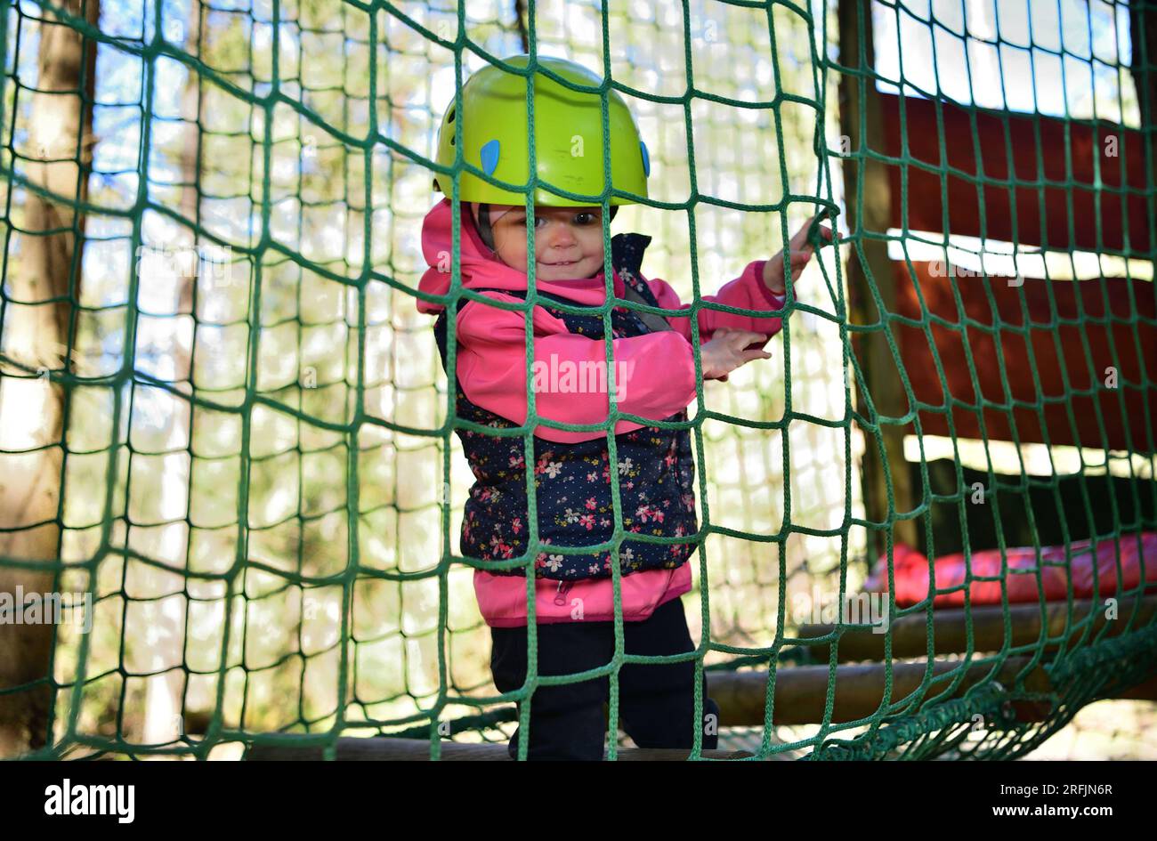 Little girl is climbing in a safety net in an amusement rope park Stock ...