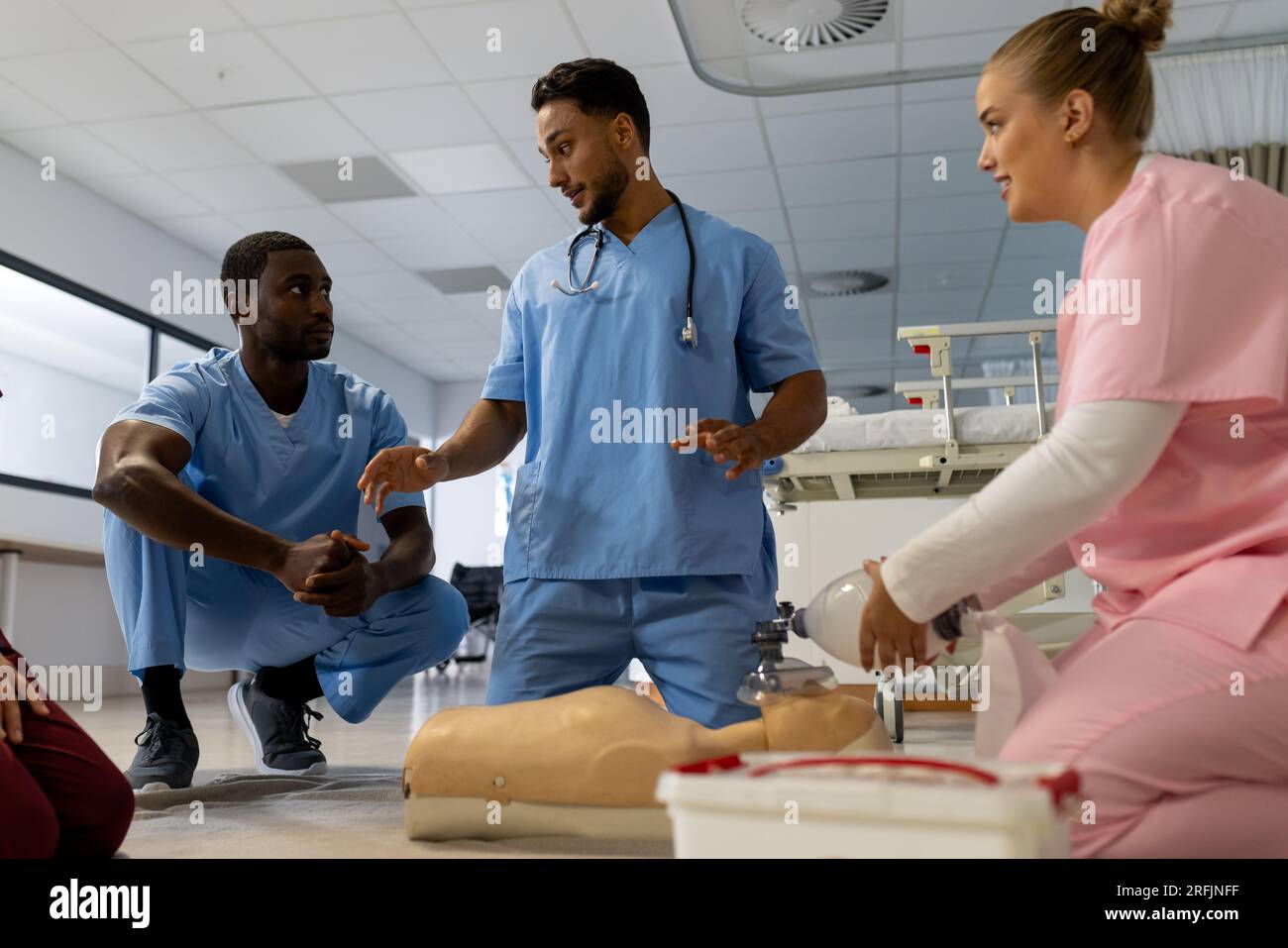 Biracial male doctor with diverse trainee doctors learning cpr on model ...
