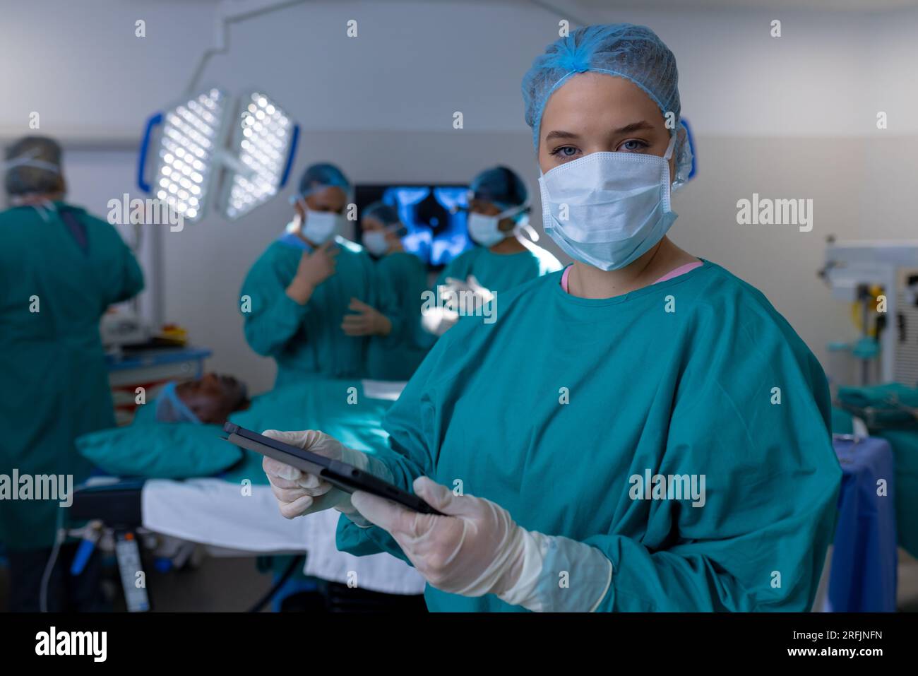 Portrait of caucasian female surgeon wearing surgical gown in operating ...