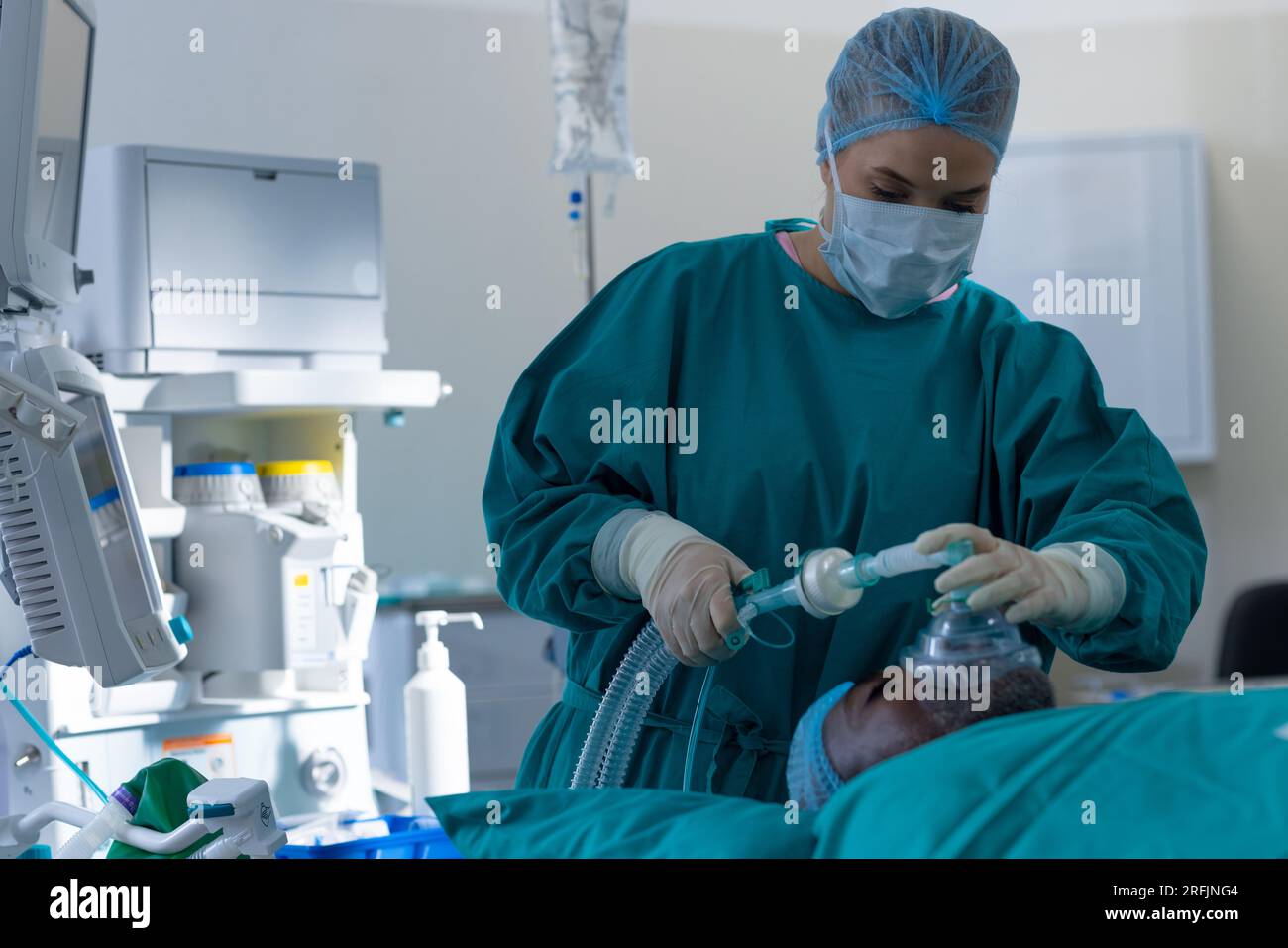 Caucasian female surgeon placing anaesthetic face mask on patient in ...