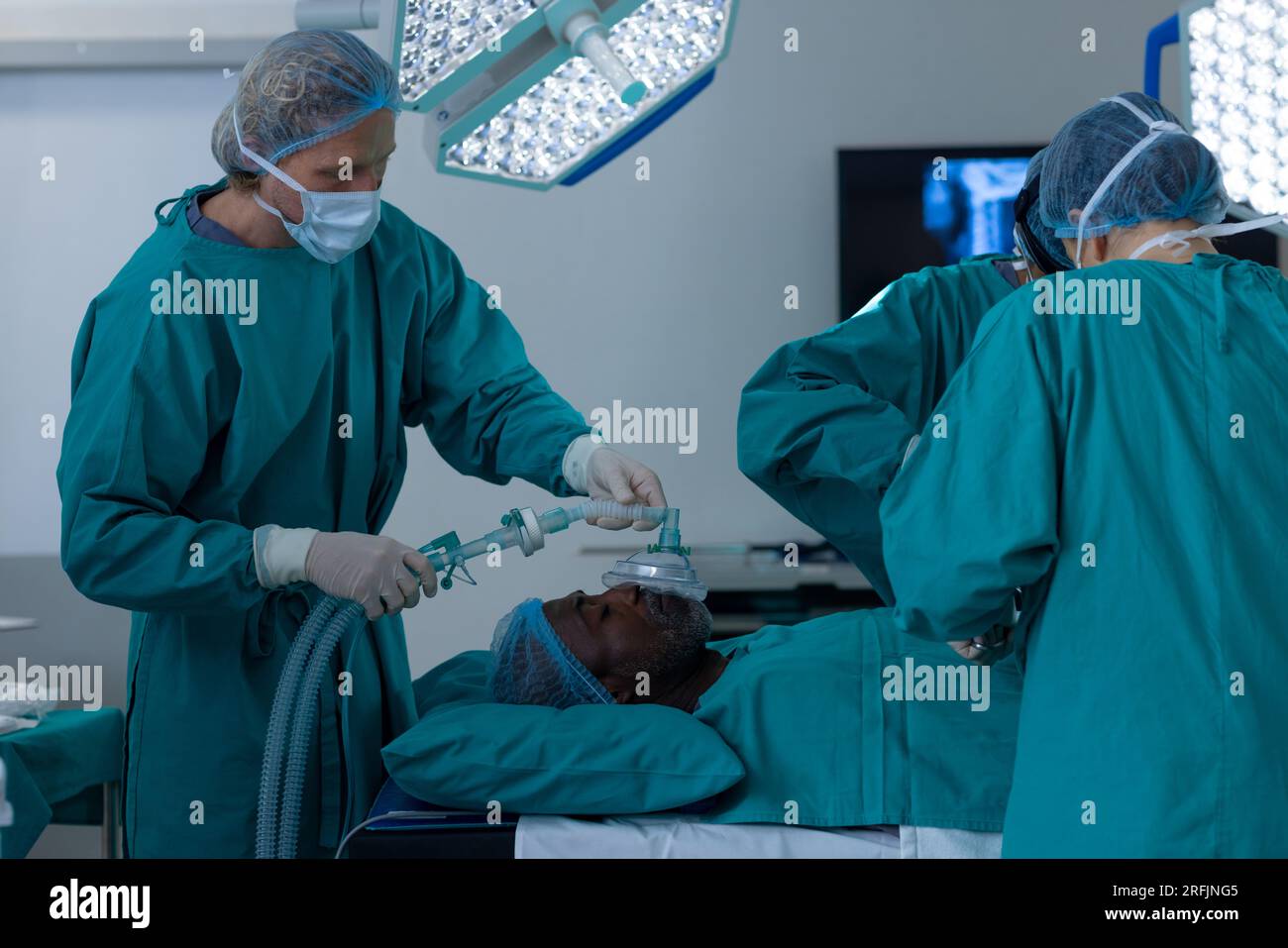 Diverse surgeons wearing surgical gowns operating on patient in ...