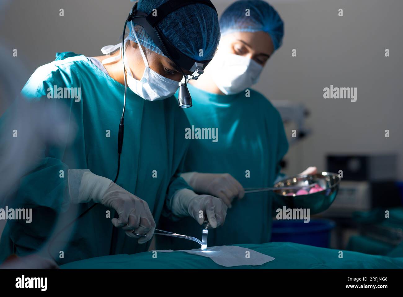 Diverse surgeons wearing surgical gowns operating on patient in ...