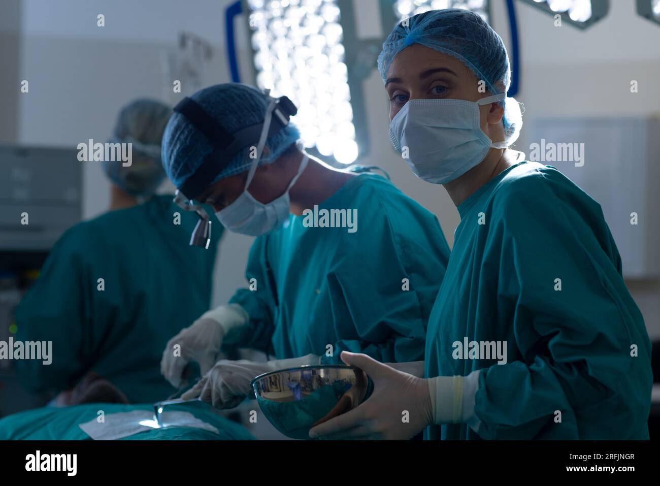 Portrait of caucasian female surgeon wearing surgical gown in operating ...