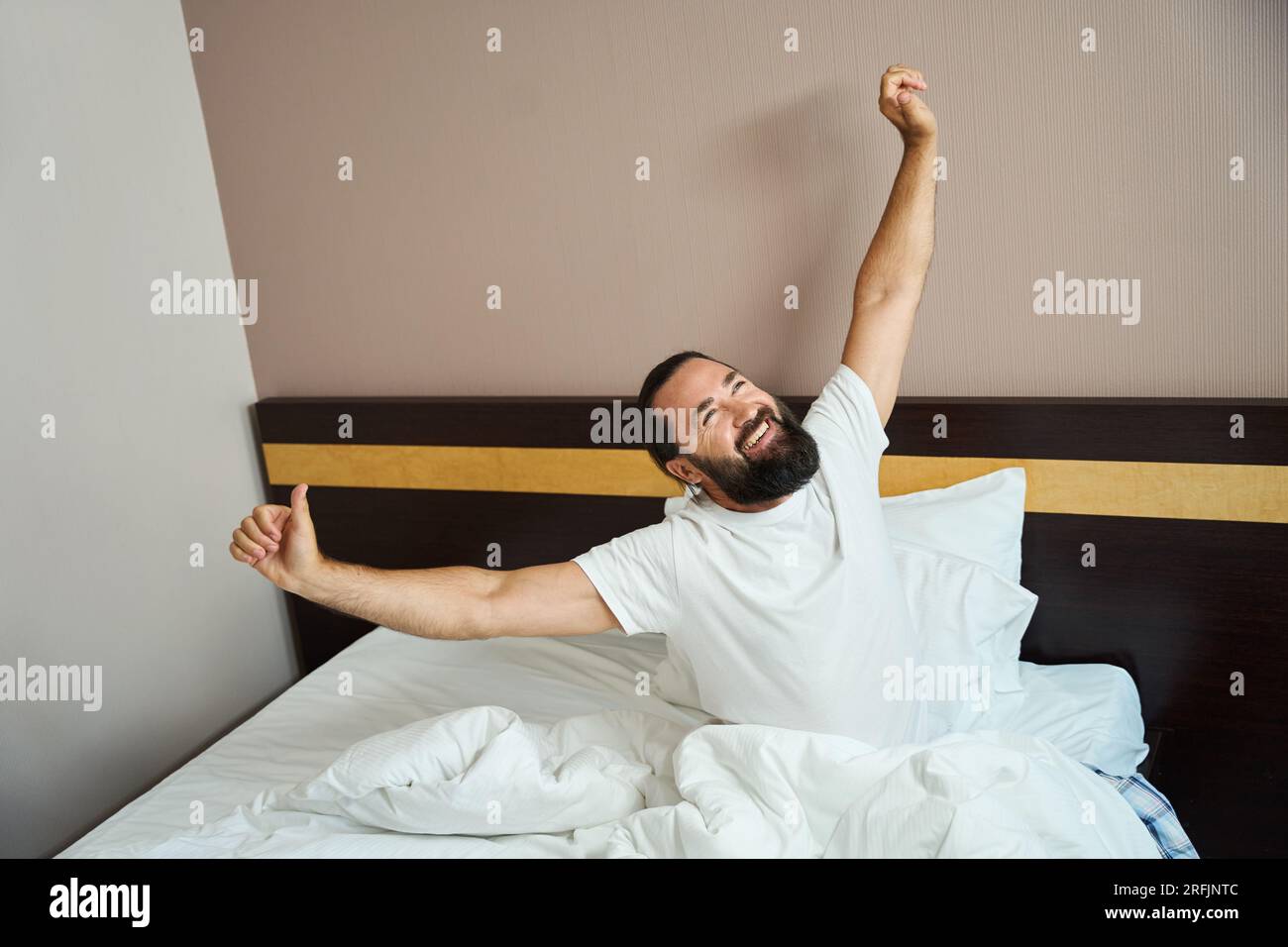 Happy man wakes up in a cozy hotel room Stock Photo - Alamy