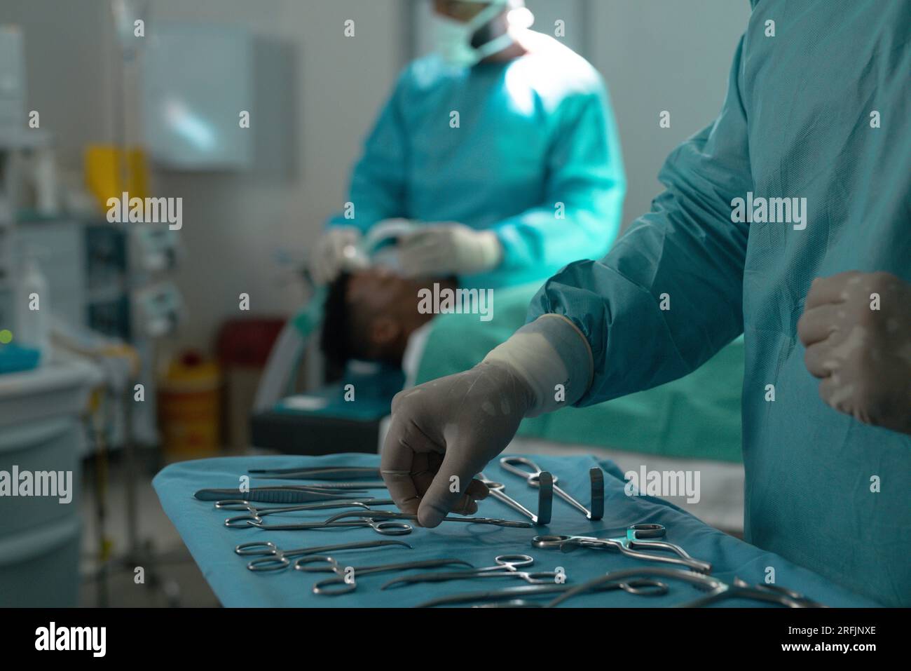 Midsection of biracial male surgeon preparing surgical instruments in ...