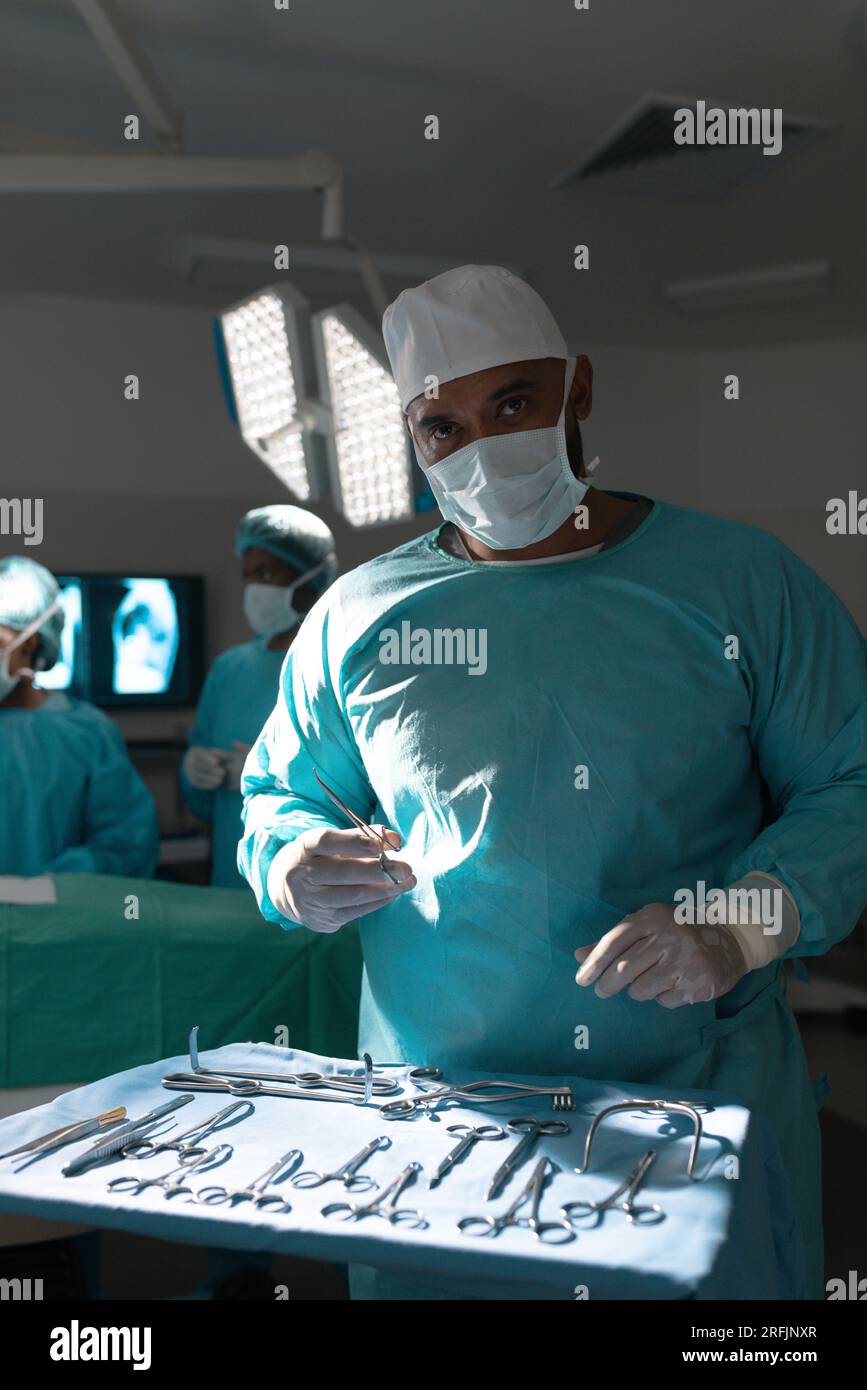 Portrait of biracial male surgeon wearing surgical gown in operating ...