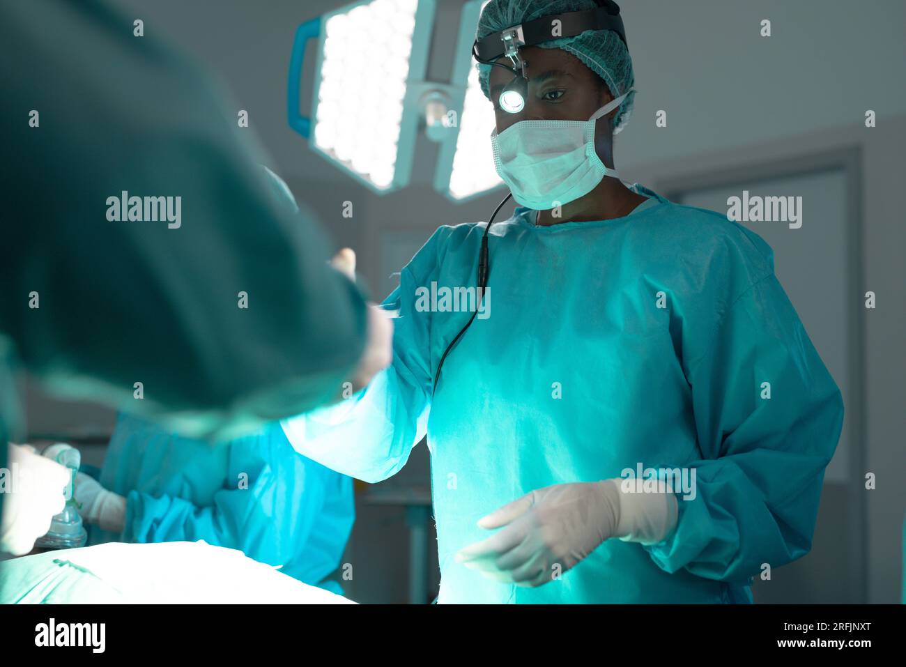 Diverse surgeons wearing surgical gowns operating on patient in ...