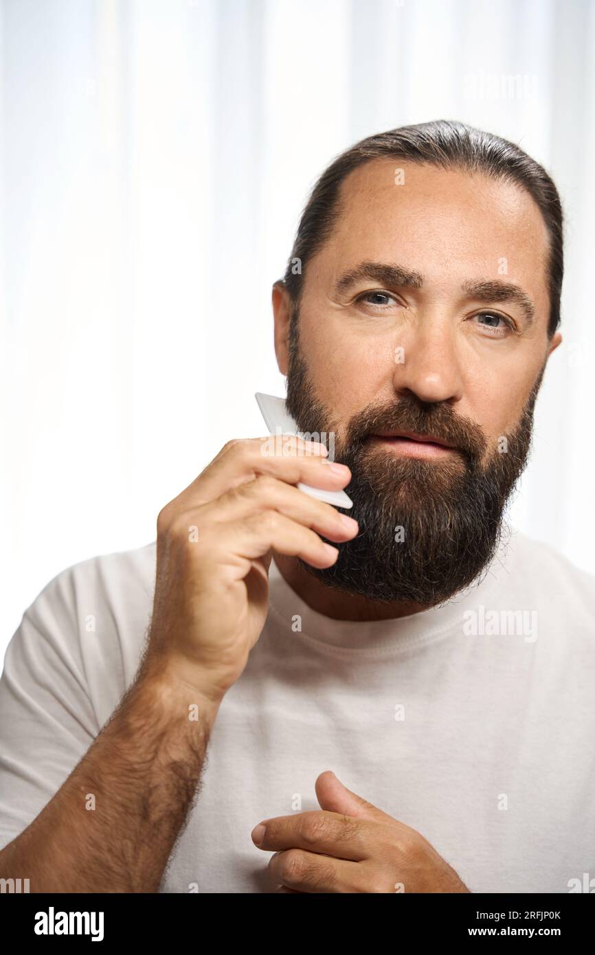 Adult male combing his thick beard with a special comb Stock Photo - Alamy