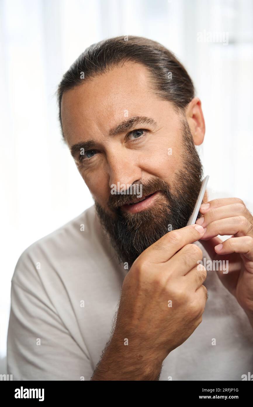 Handsome male combing his thick beard with a special comb Stock Photo ...