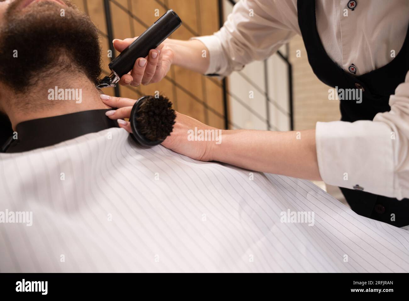 Female barber at the workplace cuts the beard of man Stock Photo - Alamy