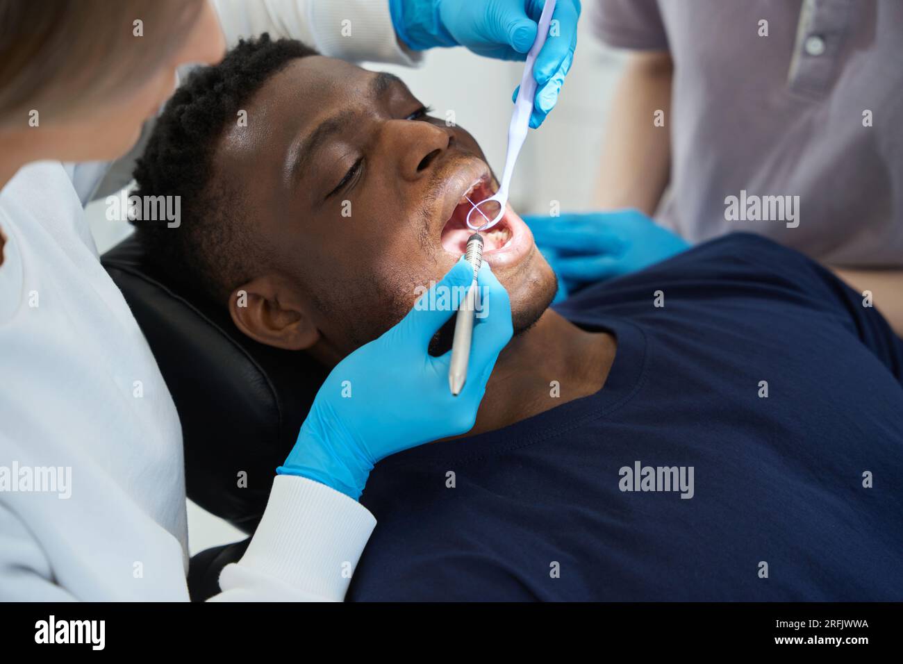 Qualified woman dentist examining male client oral cavity using mouth ...
