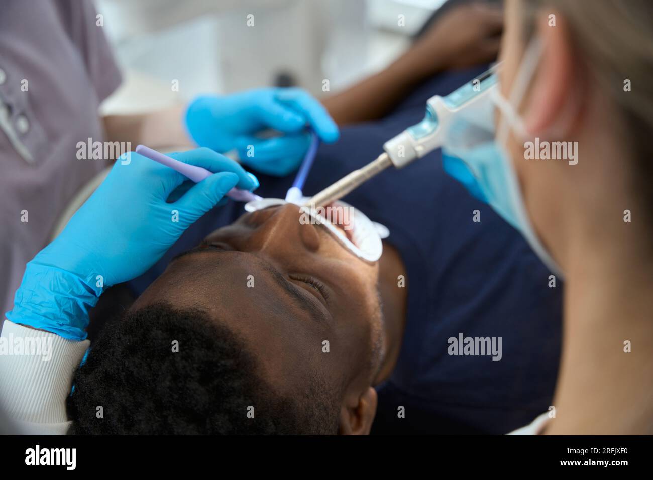 Personal of stomatology clinic treating African American client teeth ...