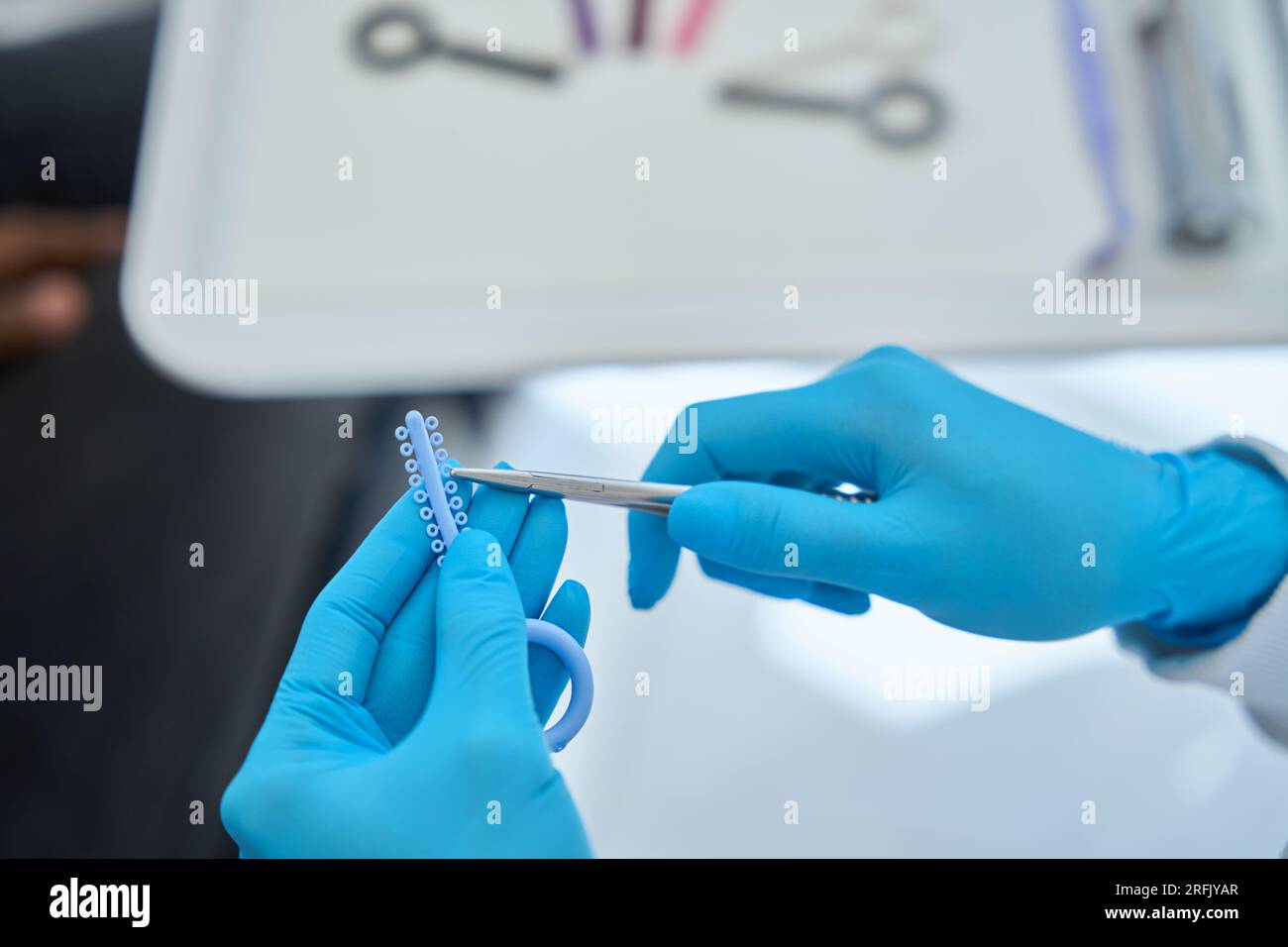 Close-up high-qualified dentist taking little rubber band that ...